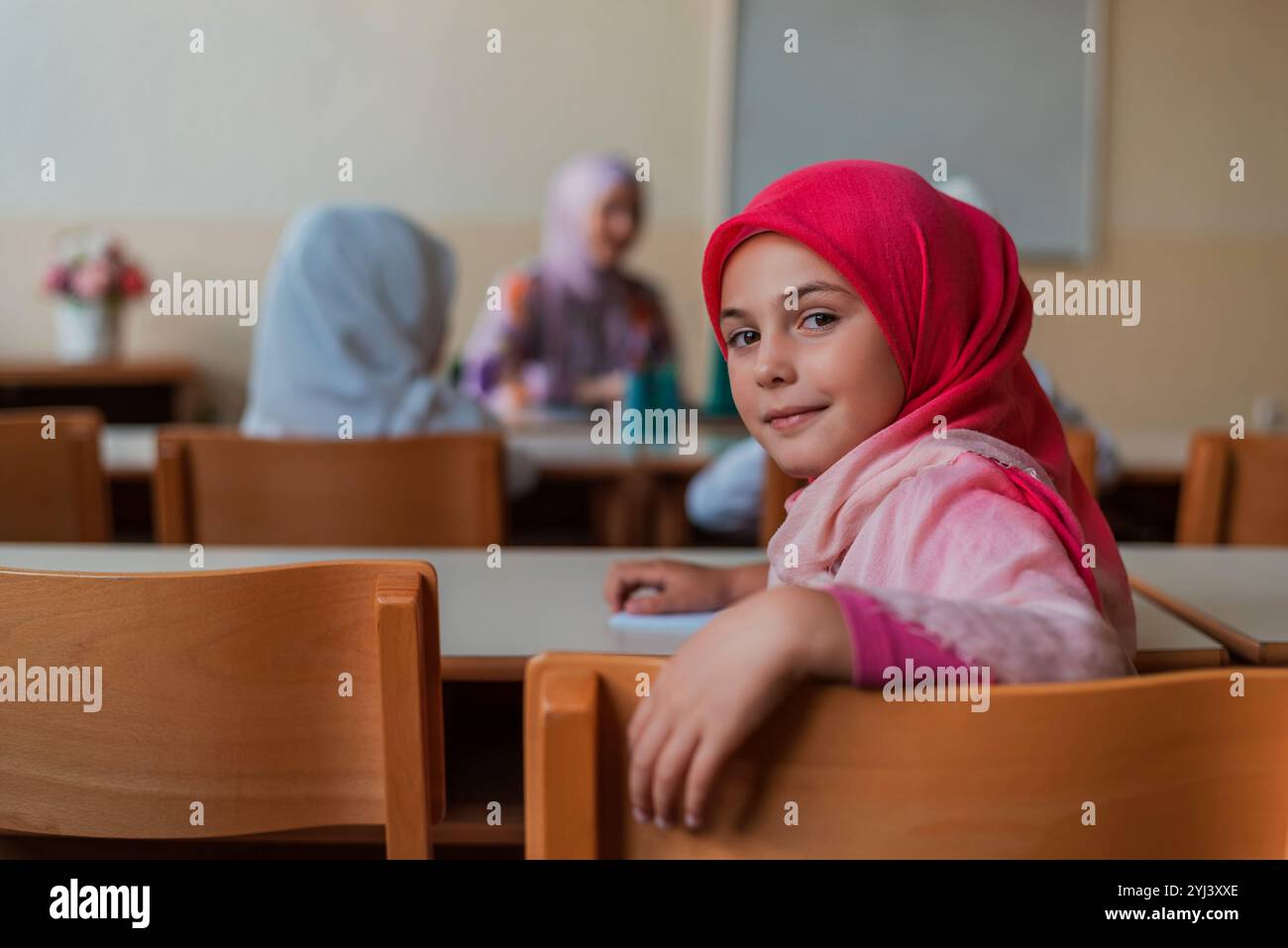 Happy Muslim girl sitting at school desk during the class in the ...
