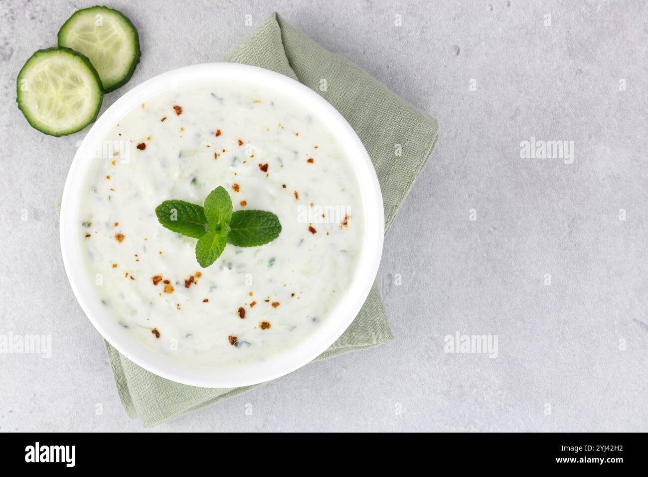 Indian raita sauce with yogurt, cucumber and mint on a gray background ...