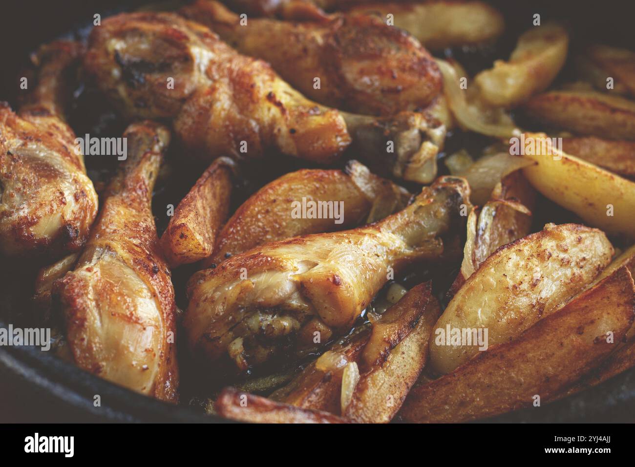 Fried chicken drumsticks with potato slices, in a clay pan, baked in ...