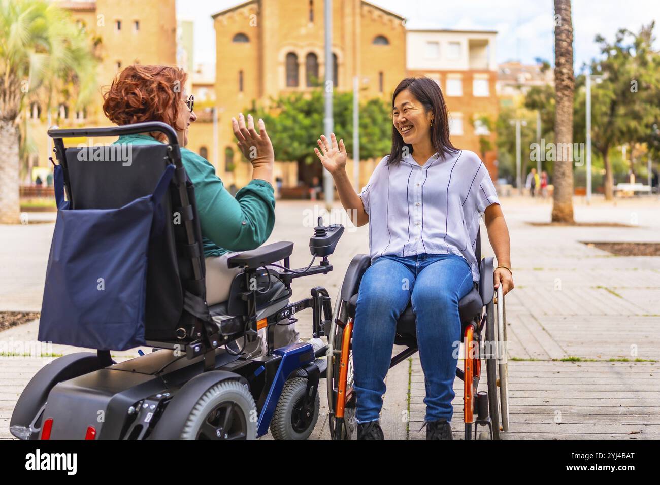 Two multi-ethnic women with disabilities in wheelchairs saying goodbye ...