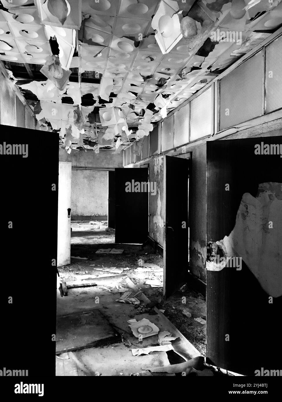 A monochrome image of a dilapidated hallway featuring scattered debris ...