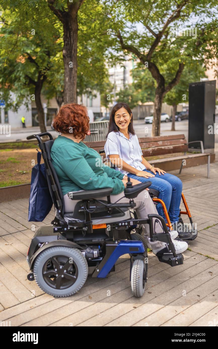 Vertical side view photo of two multi-ethnic women with disabilities in ...
