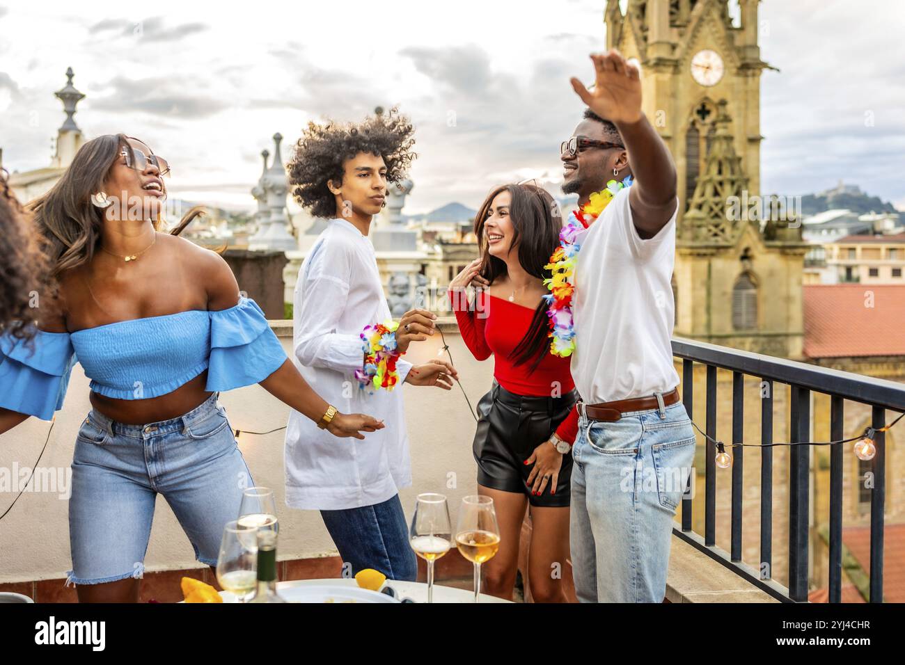 Happy multi-ethnic friends dancing together in a rooftop party at ...