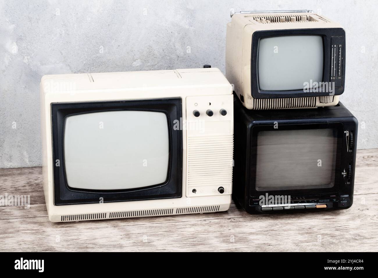 Old retro analog small TV sets stand on wooden floor front grey ...