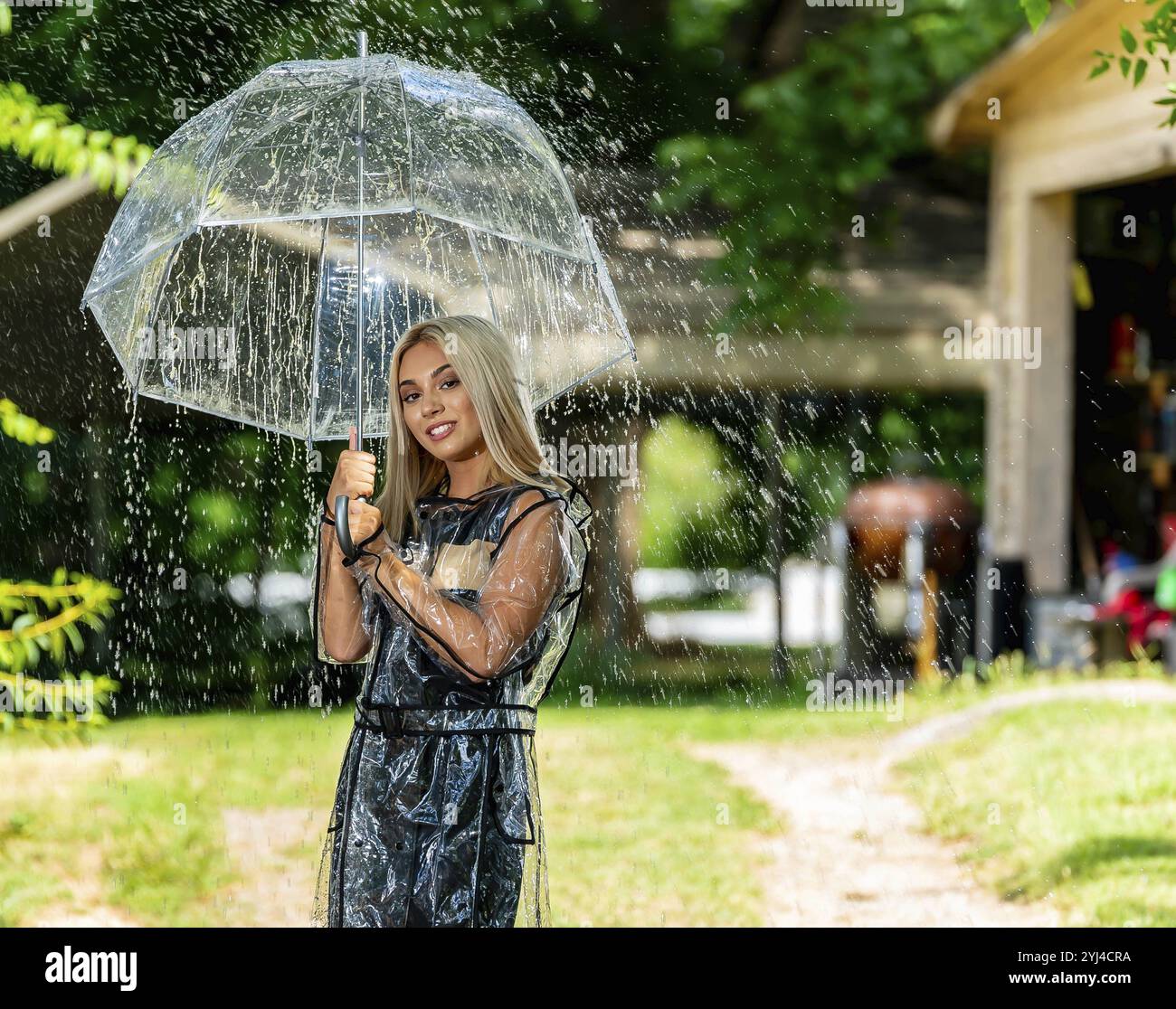 A radiant blonde model gracefully poses in the rain, donning a raincoat ...