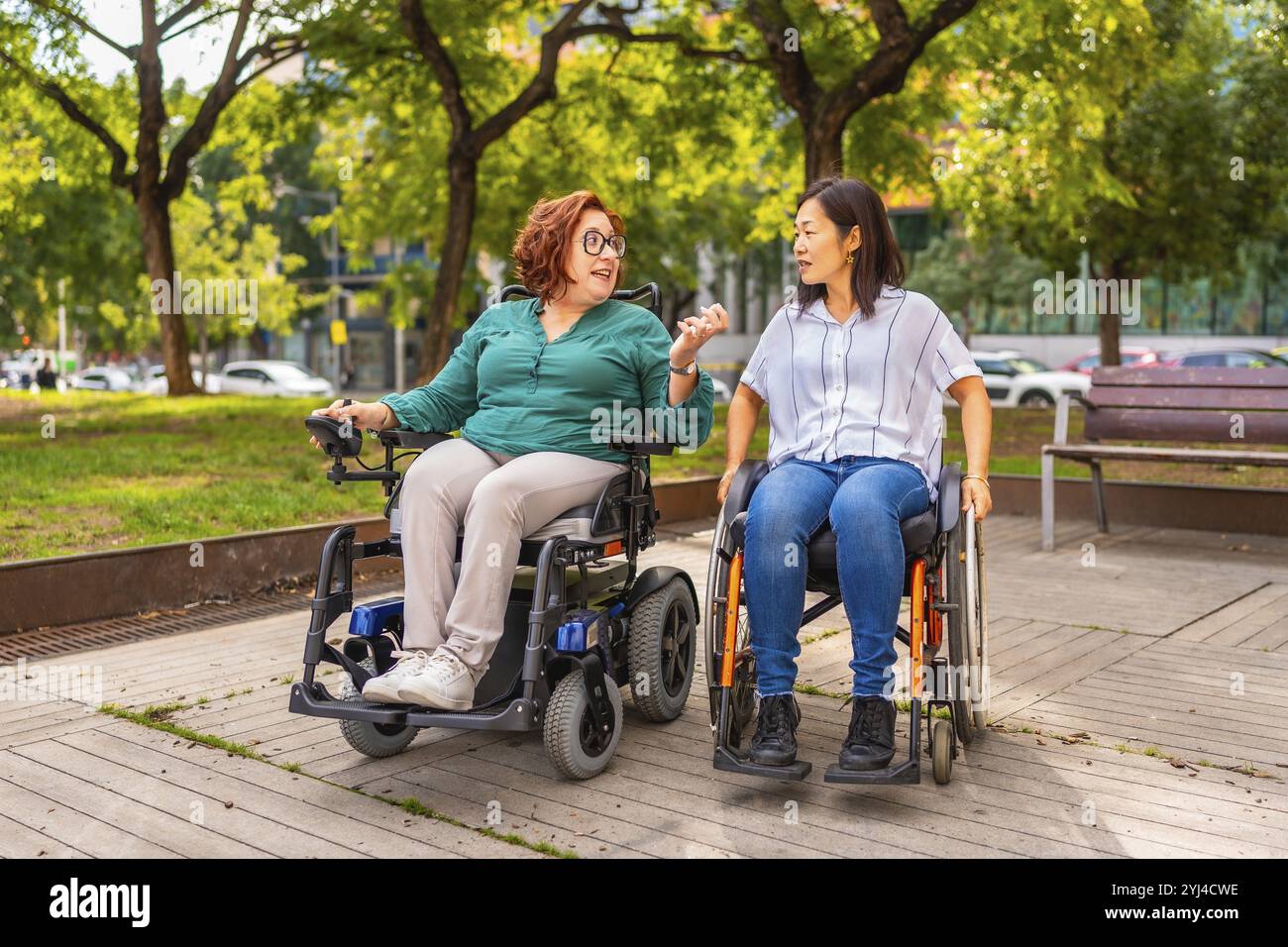 Cheerful multi-ethnic female friends with disability using wheelchair ...