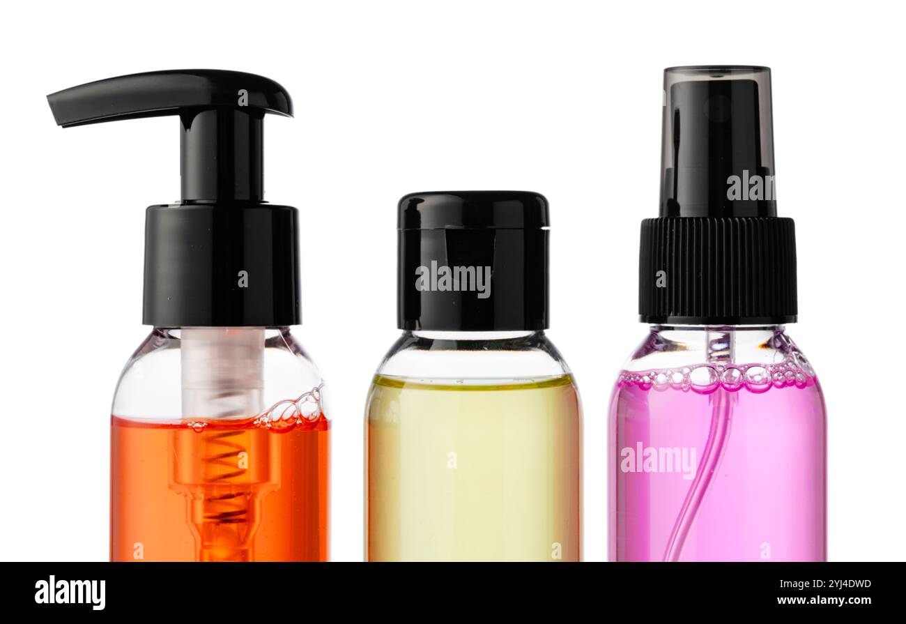 Various bottles with colored liquids and pumps arranged on white ...