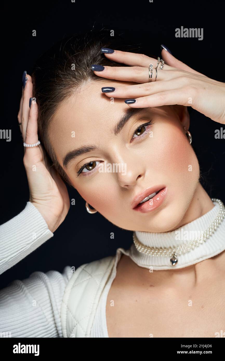 The beautiful woman gently touches her face, highlighting her elegant jewelry and refined style ...