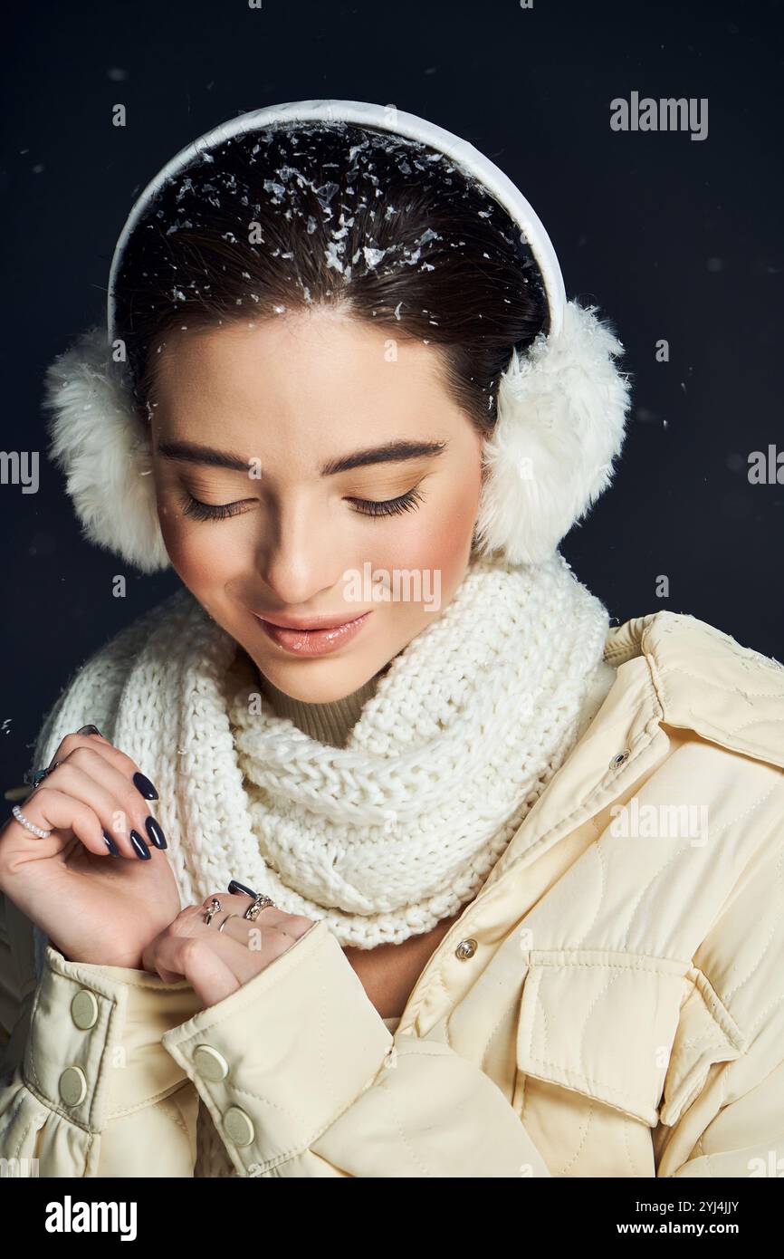 A beautiful woman, adorned in cozy winter clothing, gently enjoys the ...