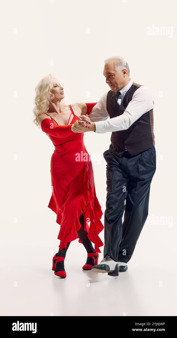 Elderly woman and senior man, elegantly dressed in red dress and black ...