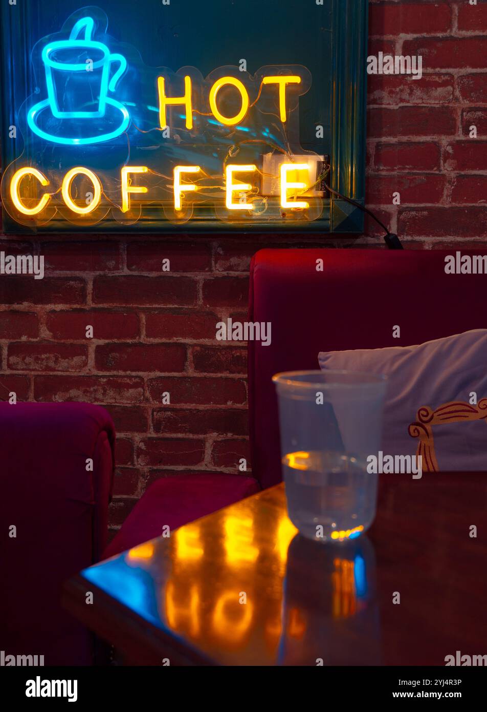 A cozy cafe interior featuring a glowing neon "Hot Coffee" sign, a red ...
