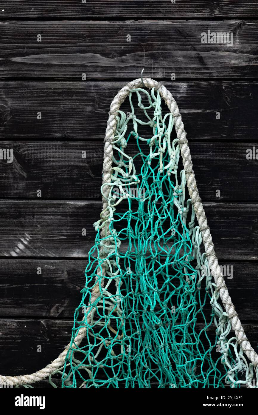 Fishing nets hanging up to dry on an old wooden black shed wall for use ...