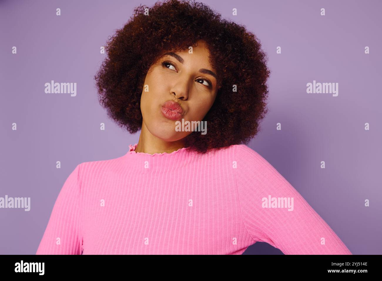 A young African American woman in a pink outfit shows her playful ...
