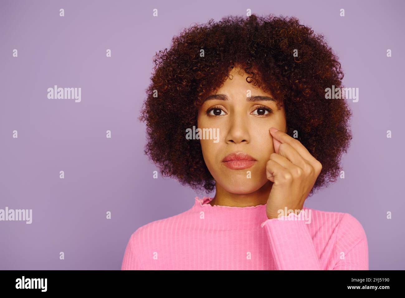 A young African American woman with curly hair conveys deep feelings ...