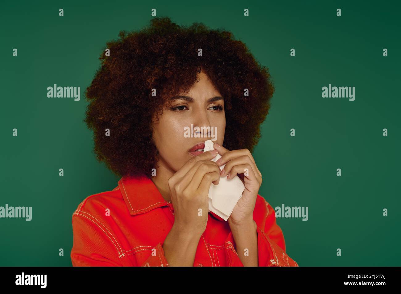 A young woman with curly hair shows deep emotion while holding a tissue ...