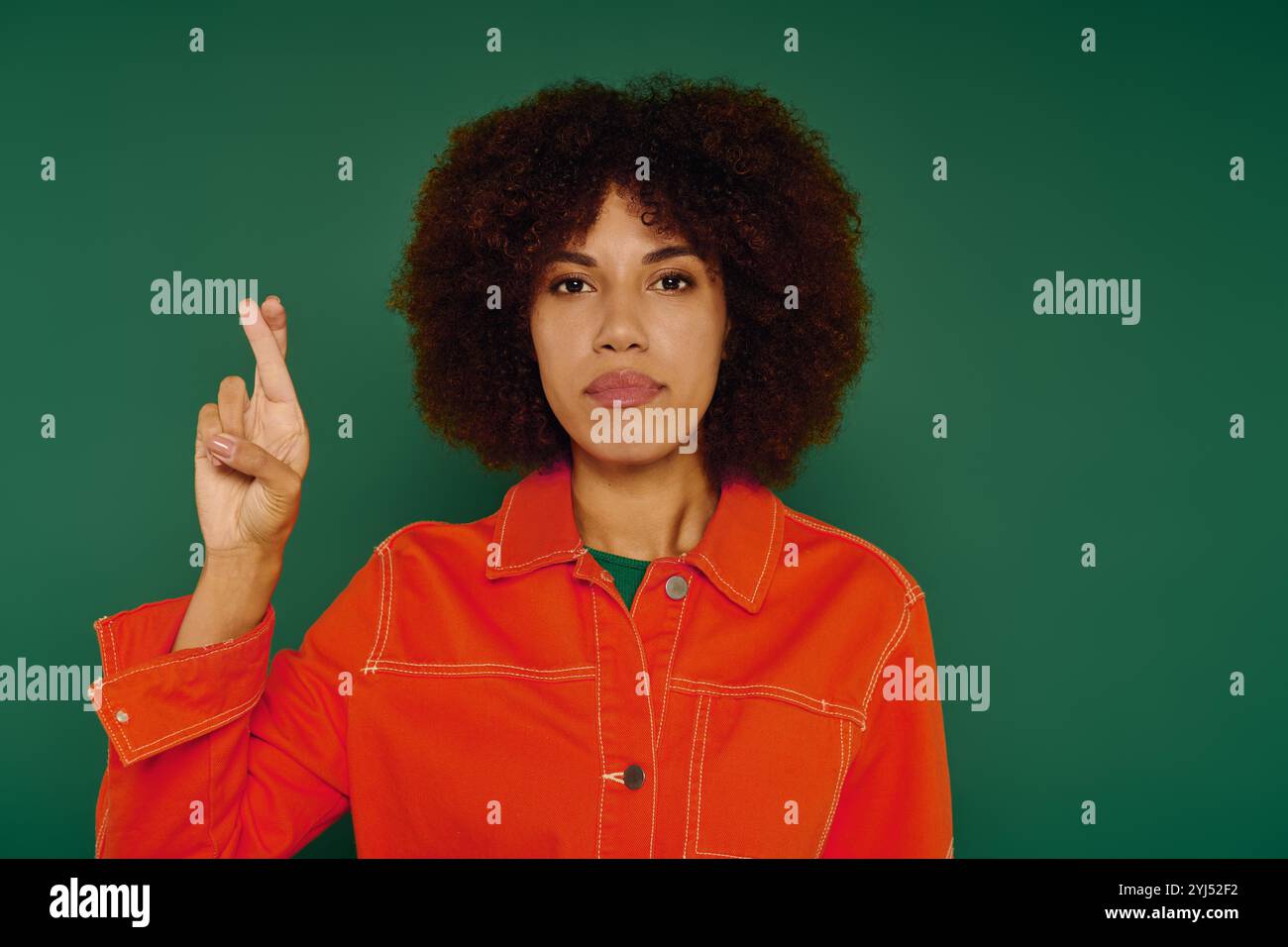 A joyful young woman with curly hair and casual clothing showcases a ...