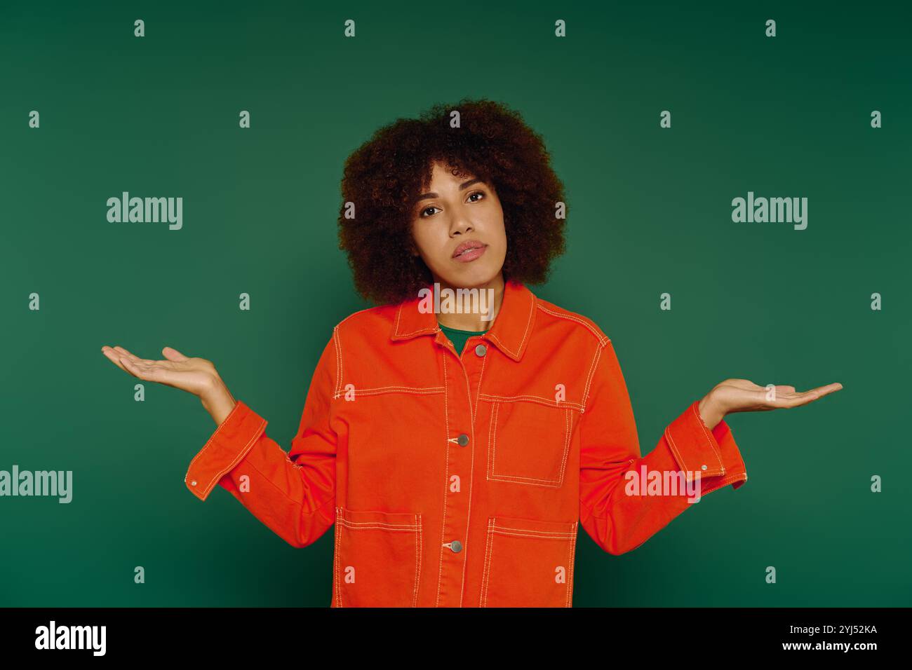 A cheerful young woman with curly hair showcases a shrug gesture while ...