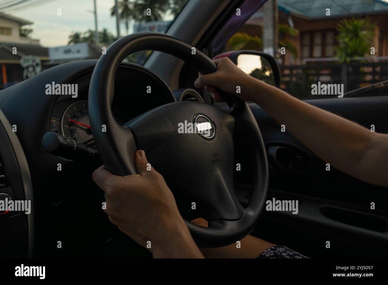 A person gripping the steering wheel of a car with both hands ...