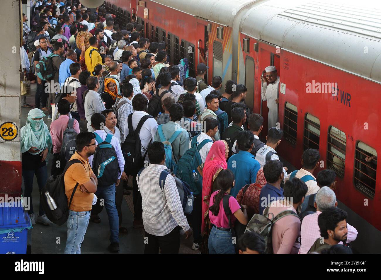 A crowd of passengers wait to board a train at the railway station in ...