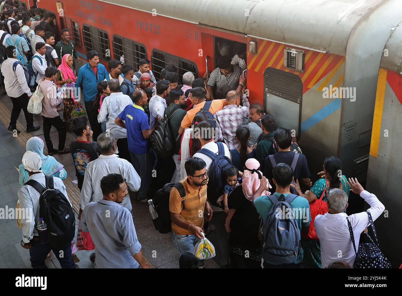A crowd of passengers scramble to board a train at the railway station ...