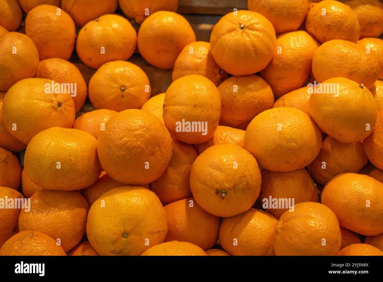 A pile of bright, fresh oranges stacked together, displaying vibrant ...