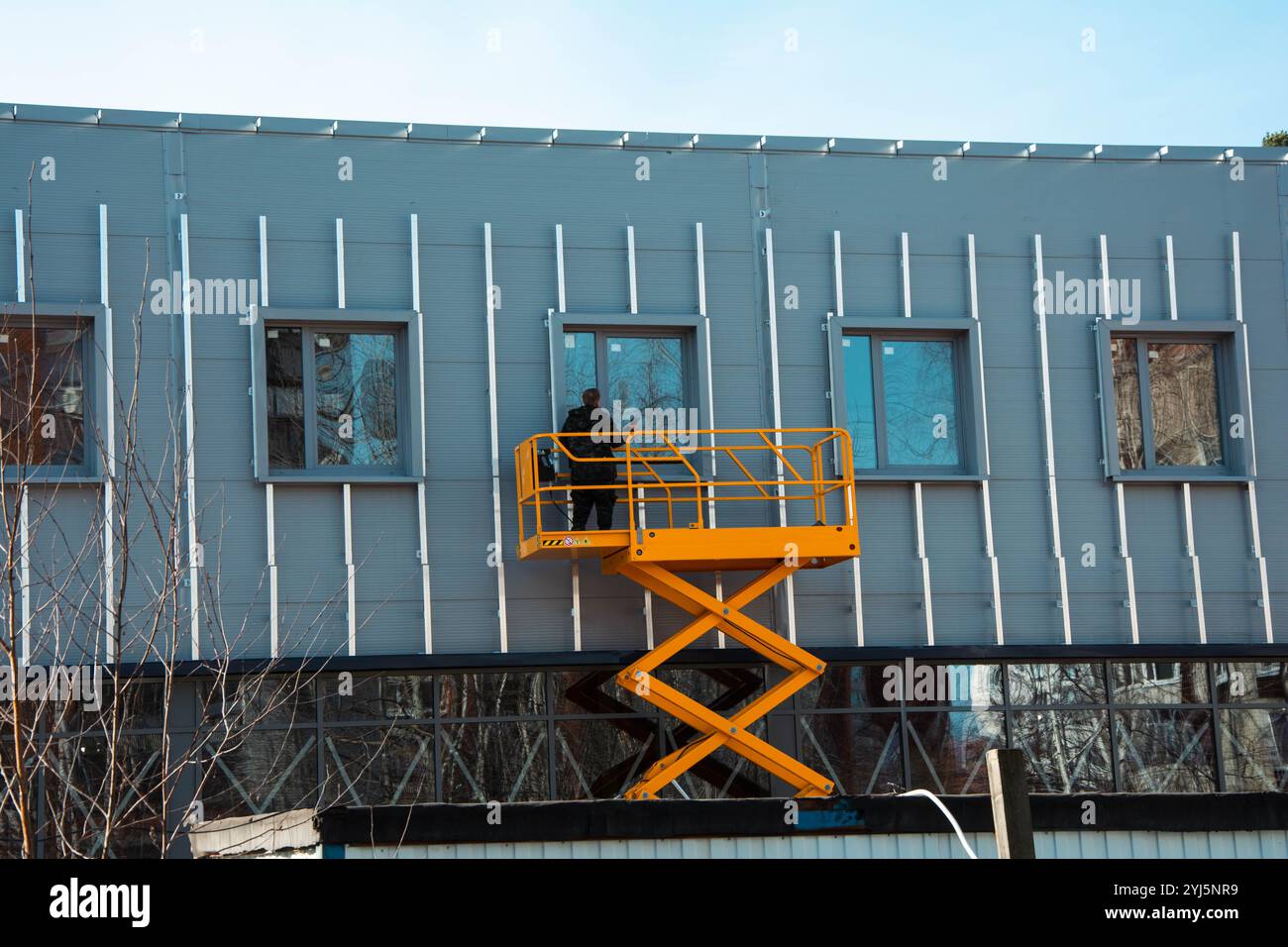 A skilled worker is using a scissor lift to mount a crate for building ...
