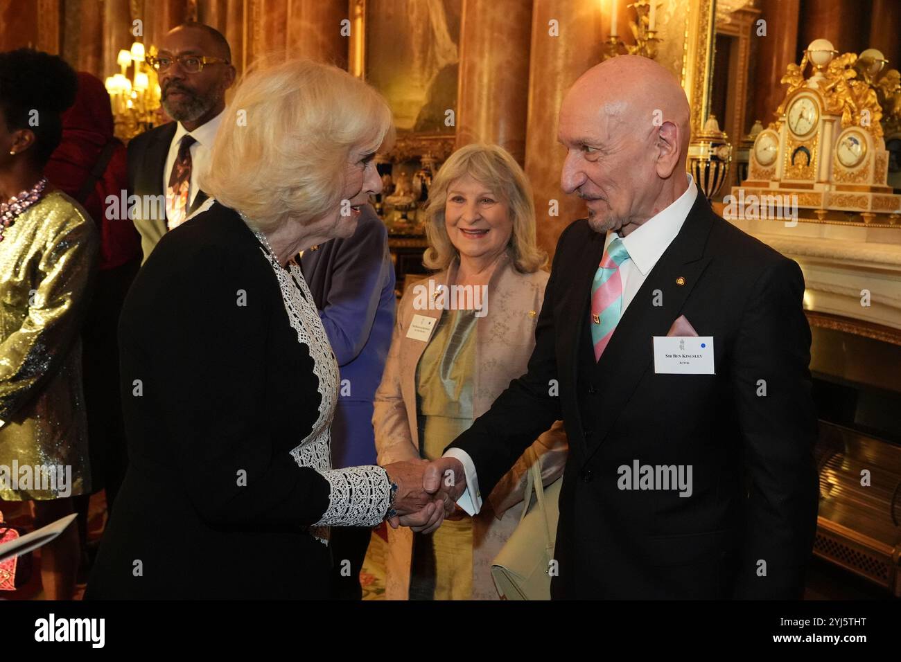 Queen Camilla, left, shakes hands with actor Ben Kingsley, right ...