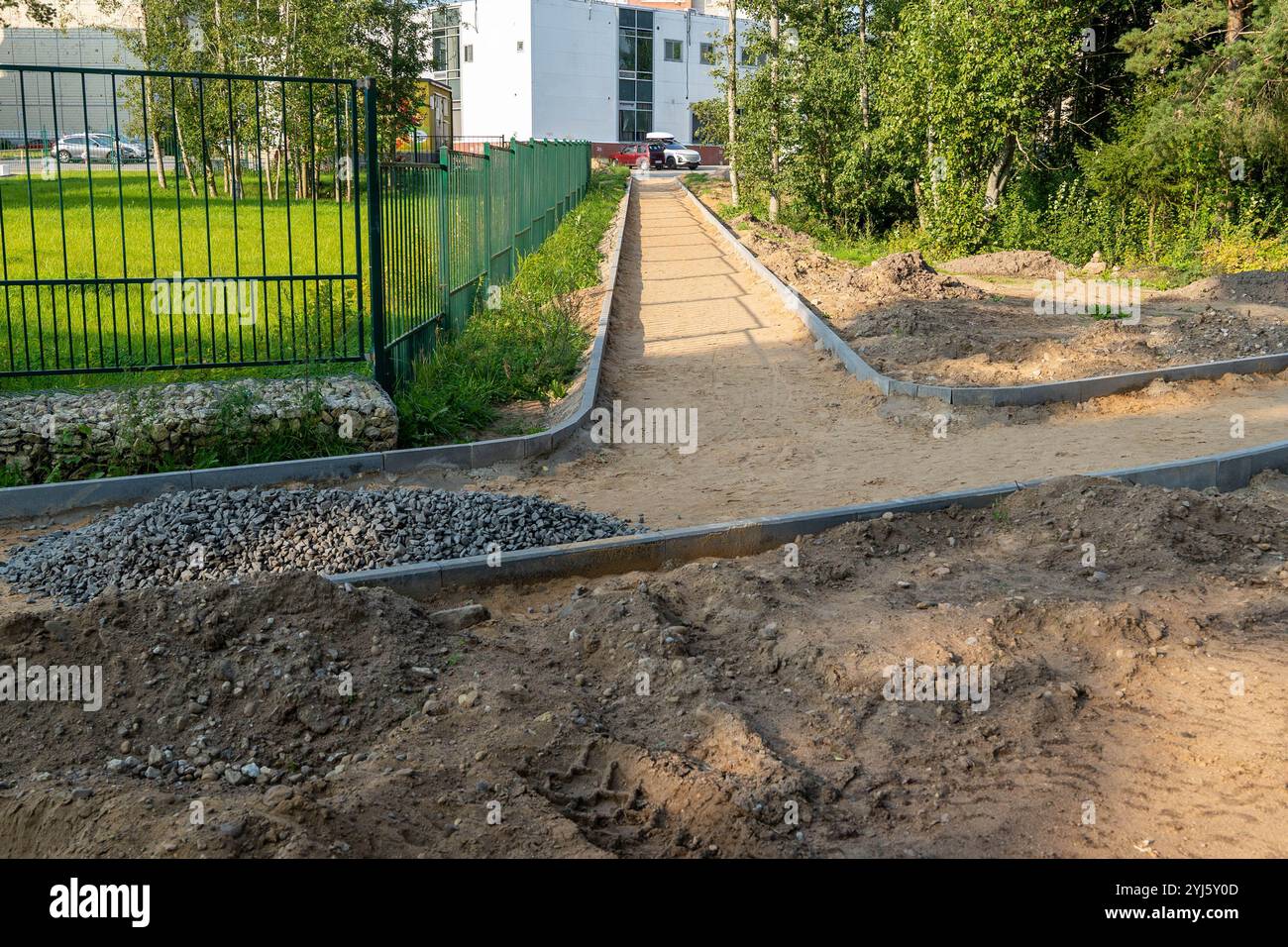 A construction site shows a pathway being built with gravel and sand ...