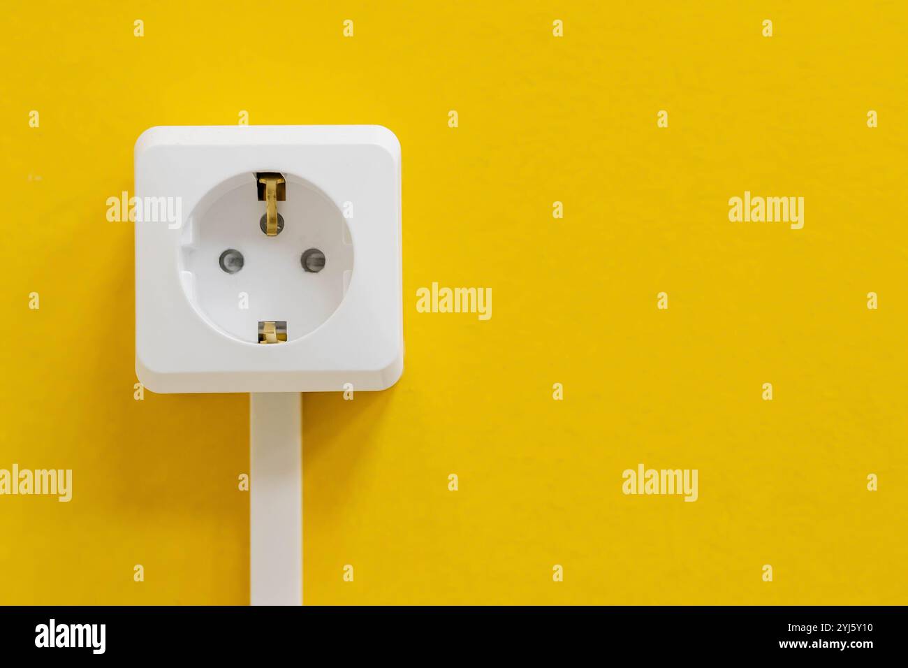 A white electrical outlet is mounted on a vibrant yellow wall Stock ...