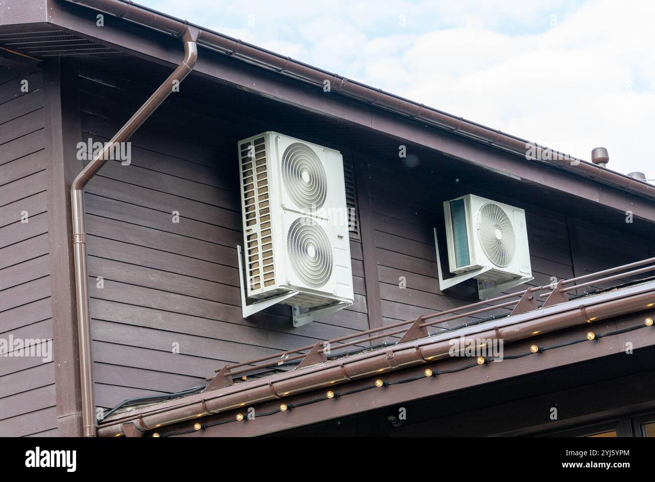 Two white air conditioners cooling a wooden facade building during a ...