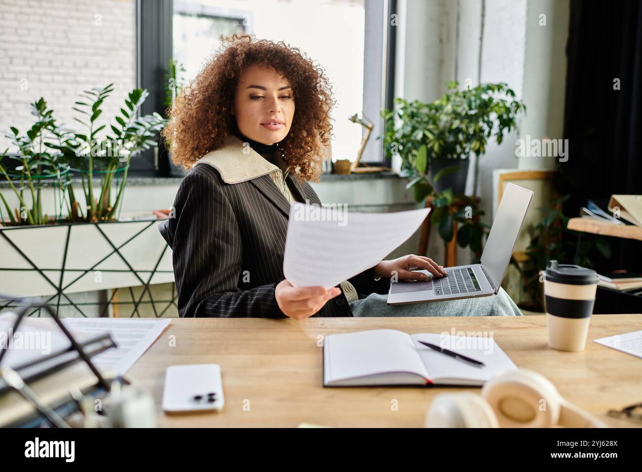 A determined woman is reading papers while seated at her desk ...