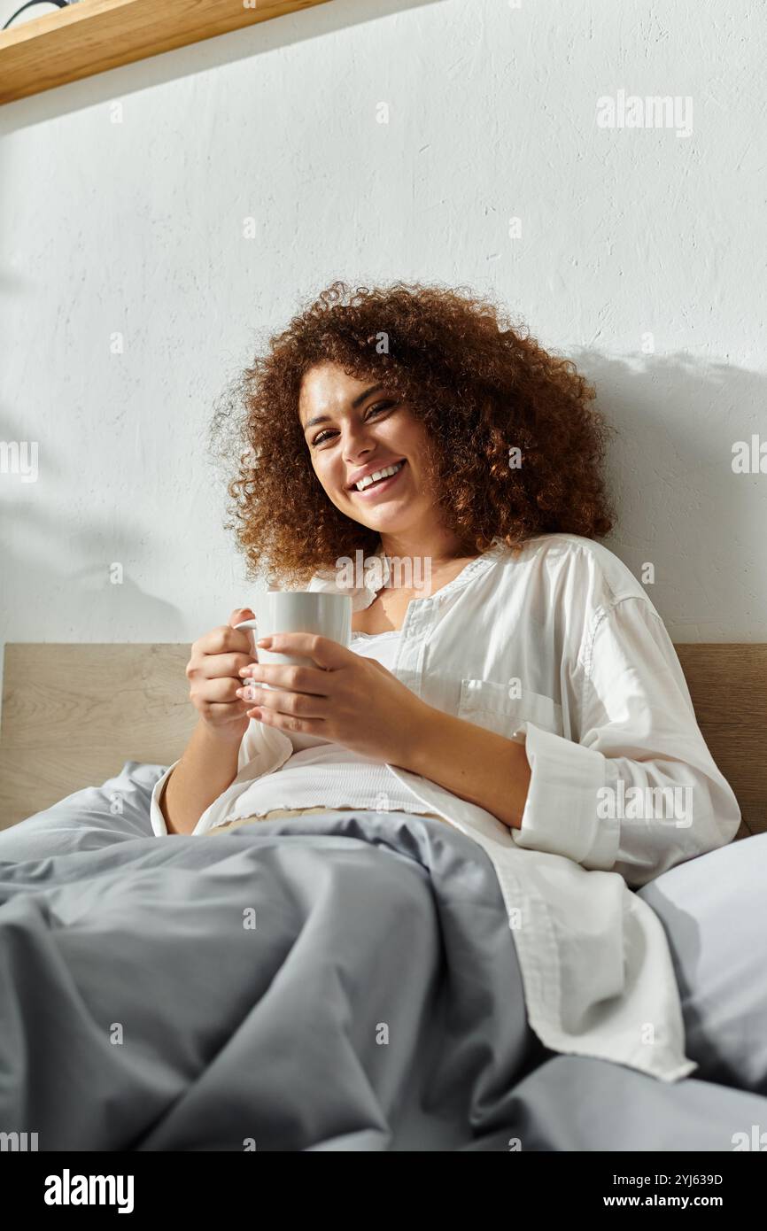 The woman smiles warmly as she savors her drink in a comfortable ...