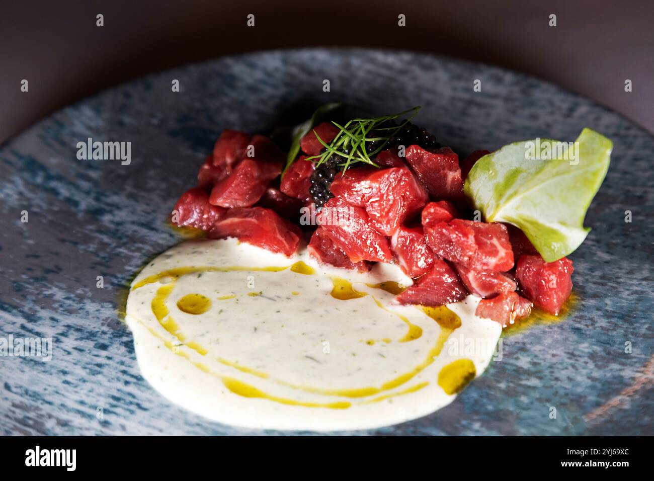 Steak tartare served with caviar and an oyster leaf. The dish is served ...