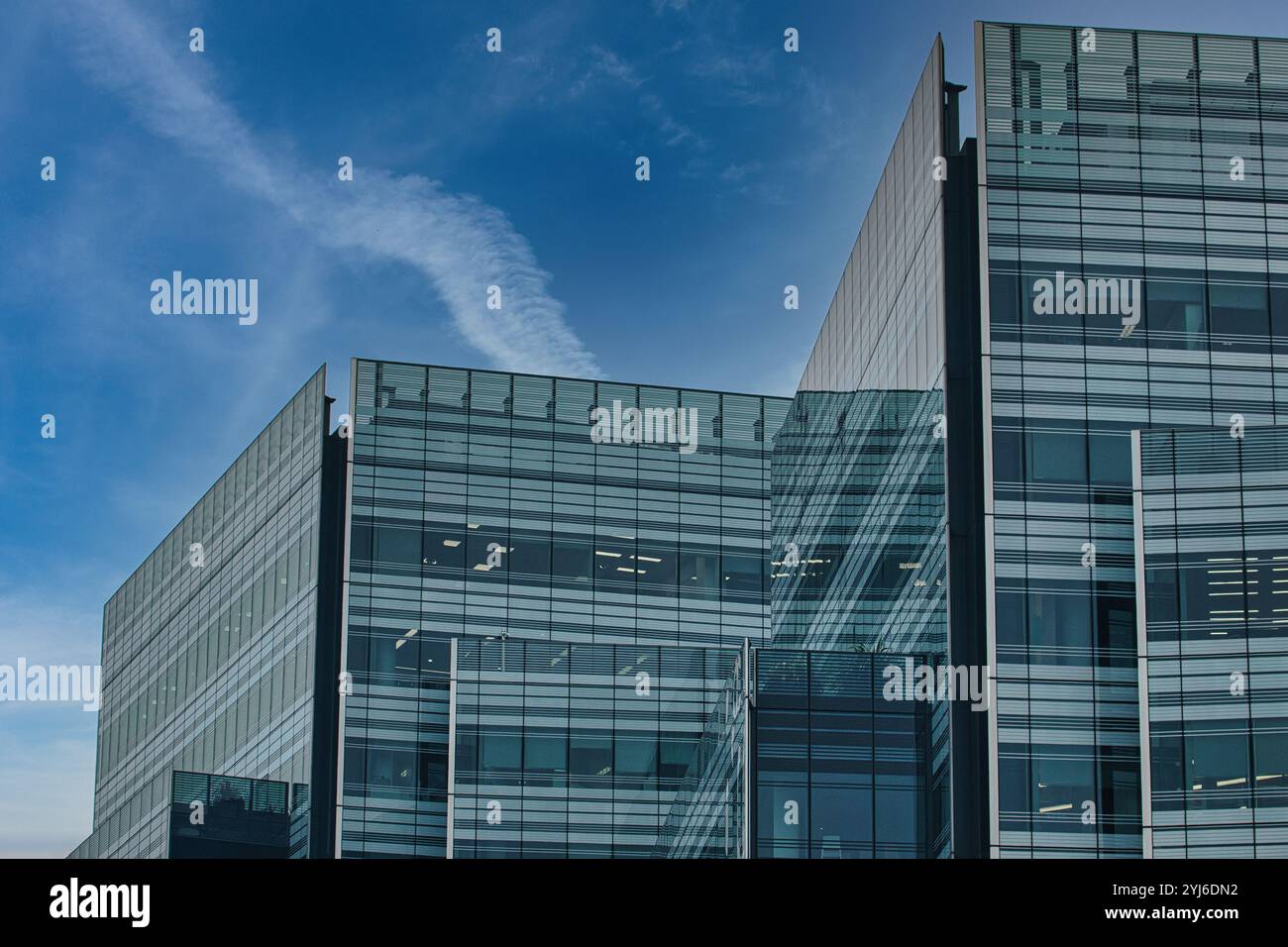 A low angle shot of a modern glass and steel skyscraper against a blue ...