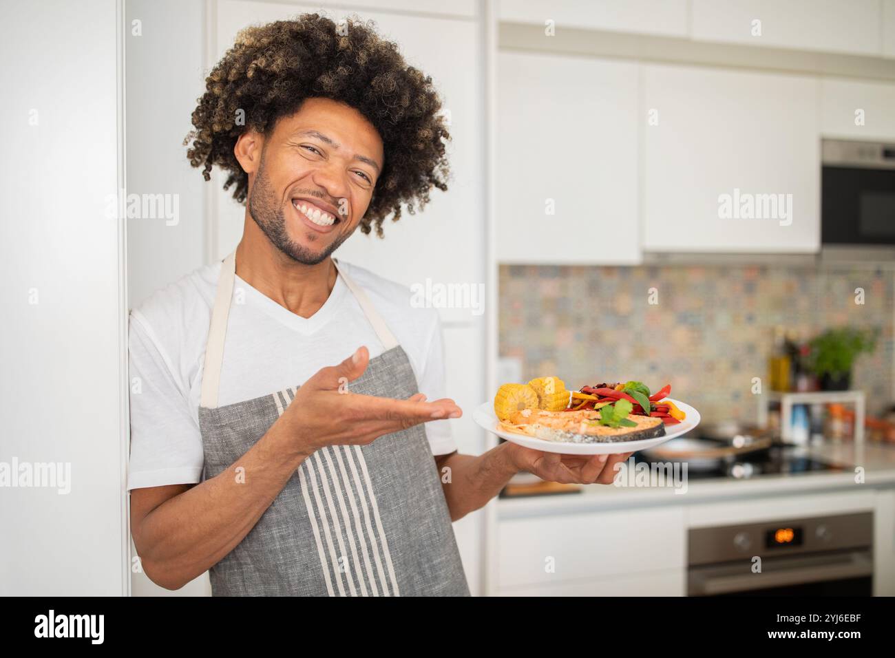 A black man with curly hair smiles proudly while showcasing a vibrant ...