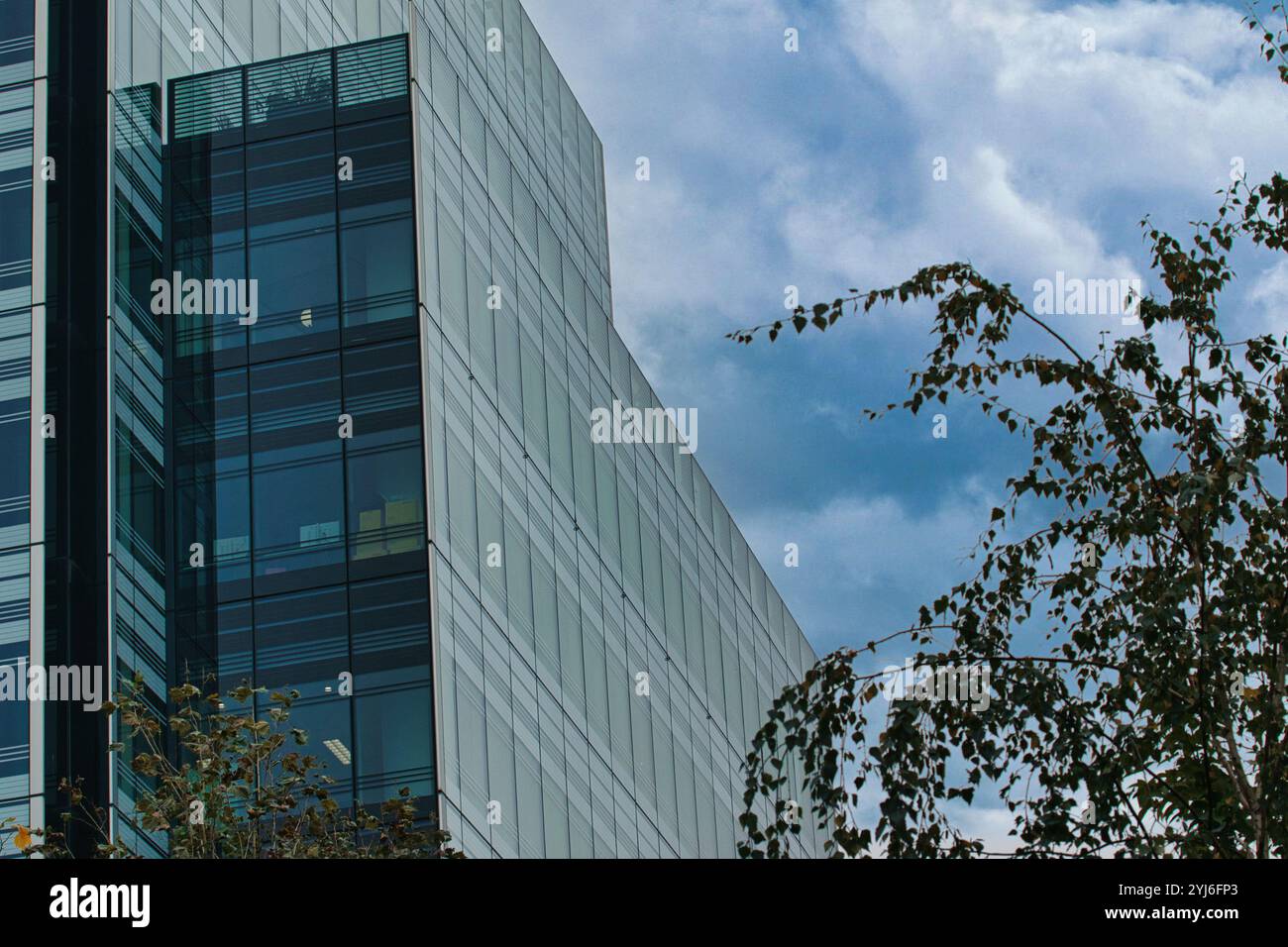The image shows a partial view of a modern glass building. The building ...