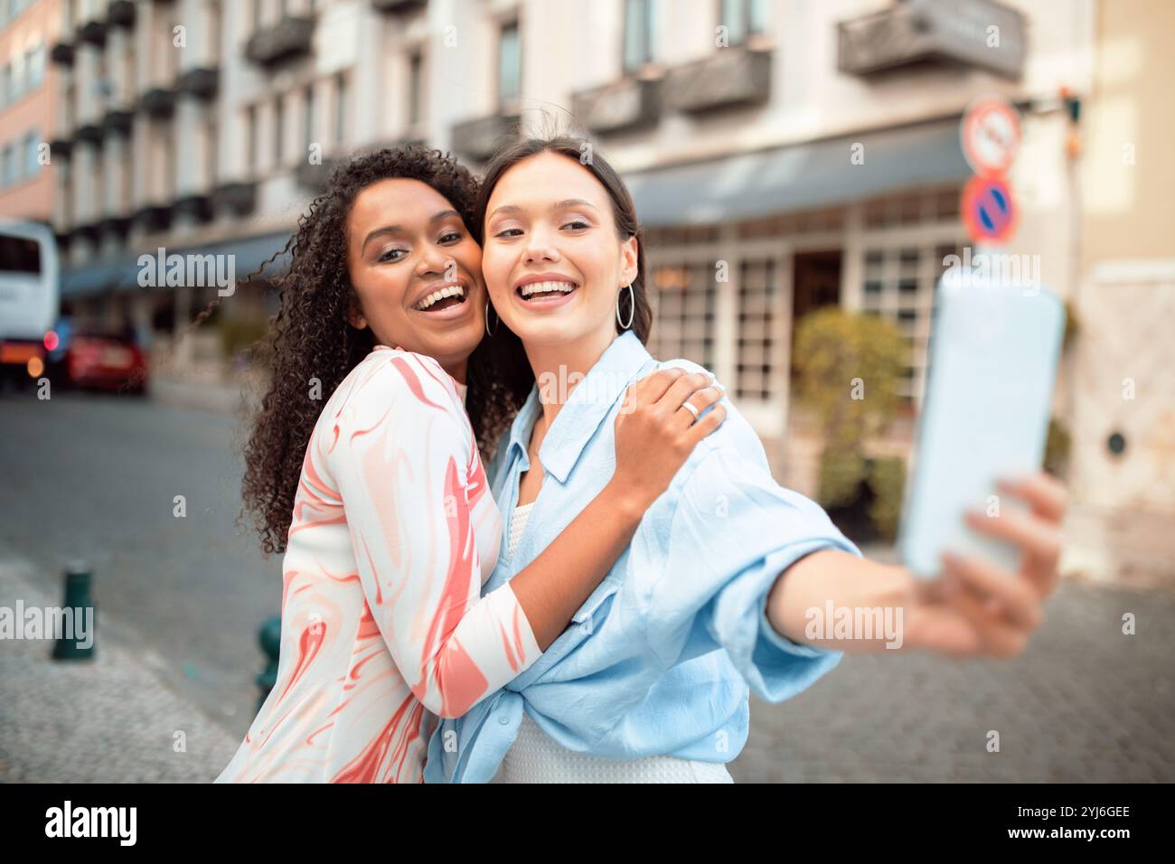 Two smiling friends pose together while taking a selfie on a vibrant ...