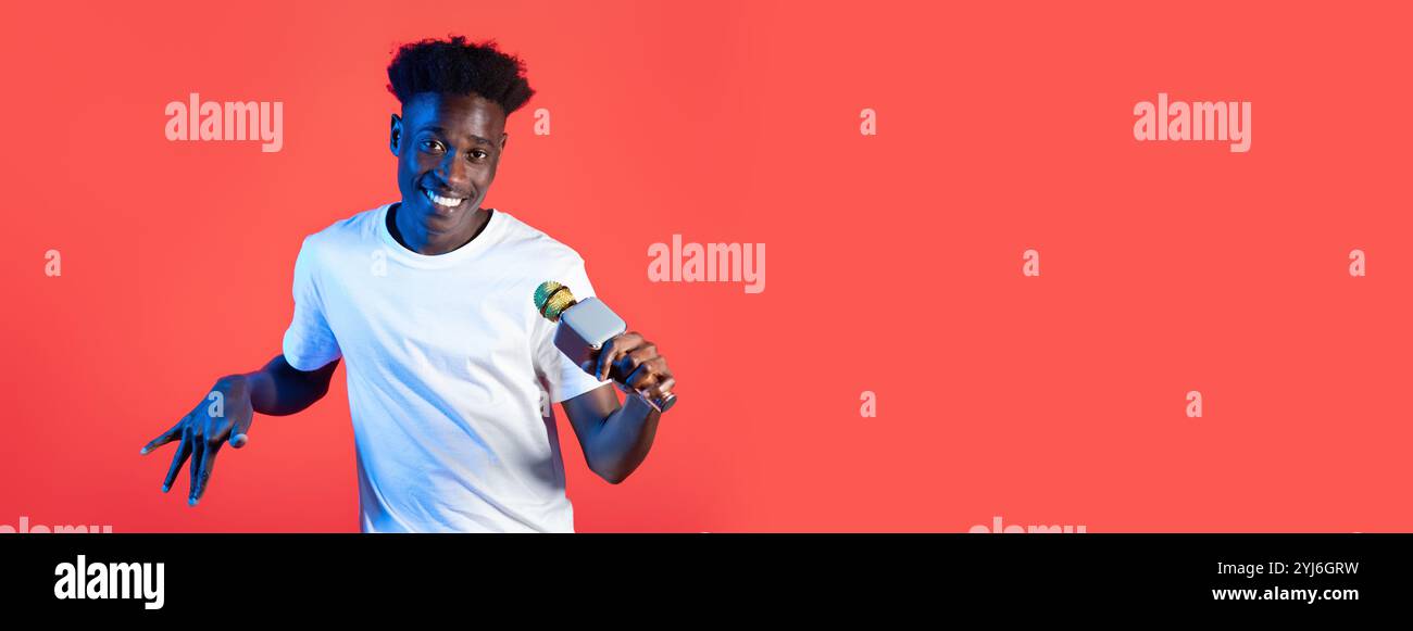 A joyful young black man confidently holds a microphone, striking a ...