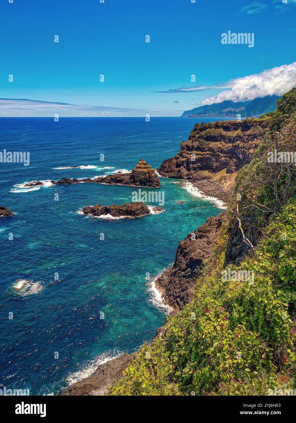 Dramatic coastal cliffs with turquoise waters and rocky formations along Madeira's rugged ...