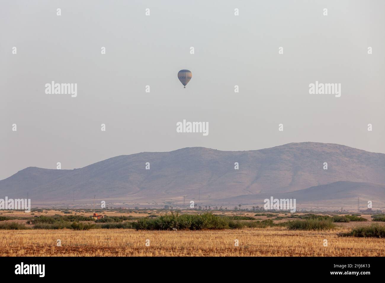 Hot air balloon flying over a desert plain at the foot of the Moroccan ...