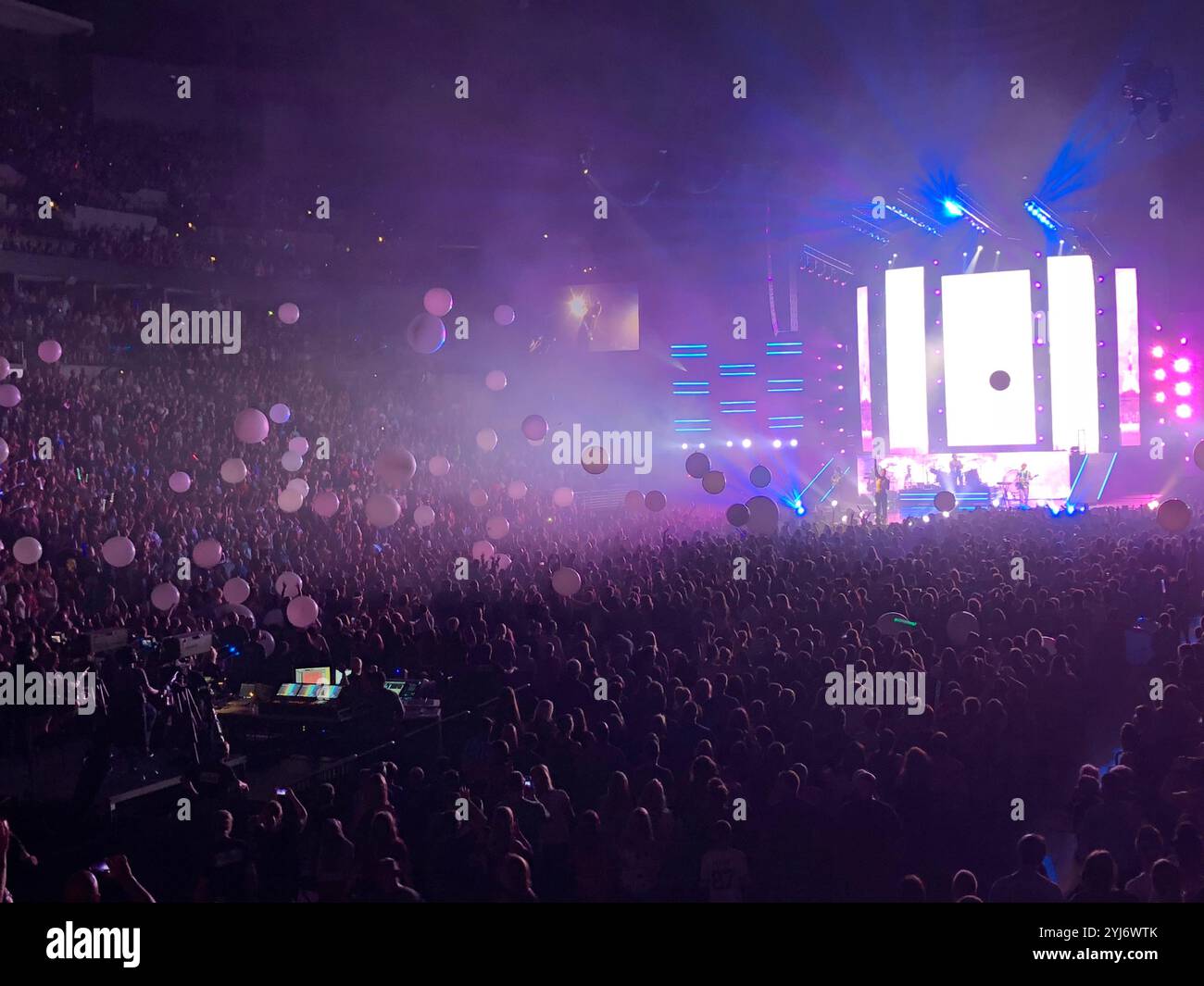 Bright fun view of a concert with light show and balloons in the crowd ...