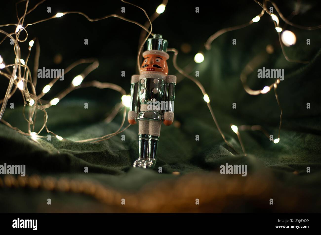 A small, wooden nutcracker is sitting on a green cloth. The nutcracker ...