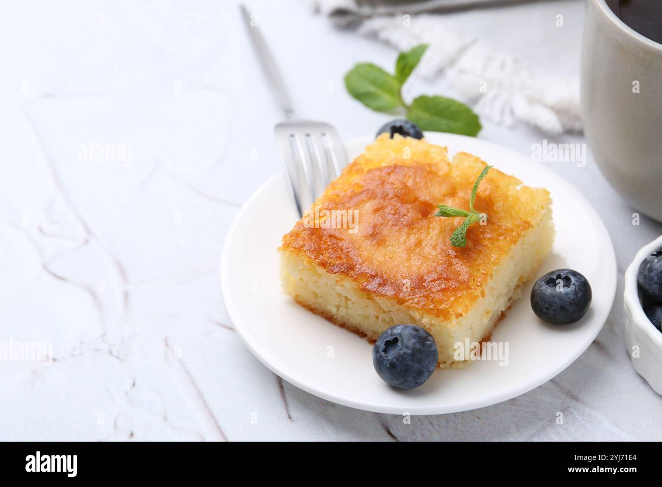 Slice of tasty semolina cake served on white textured table, closeup ...