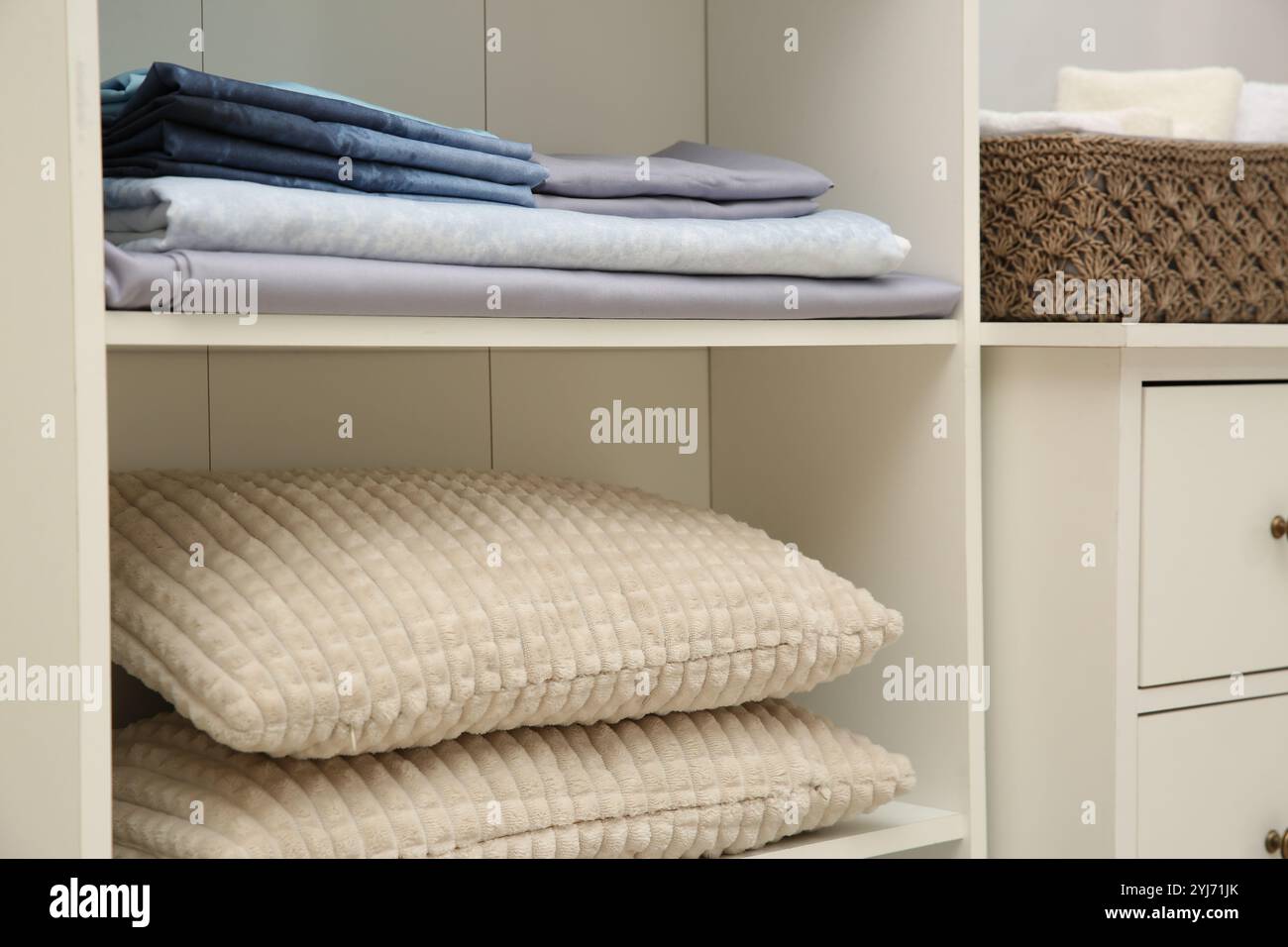 Home textile organization. Folded bedsheets and pillows on shelving unit indoors, closeup Stock ...