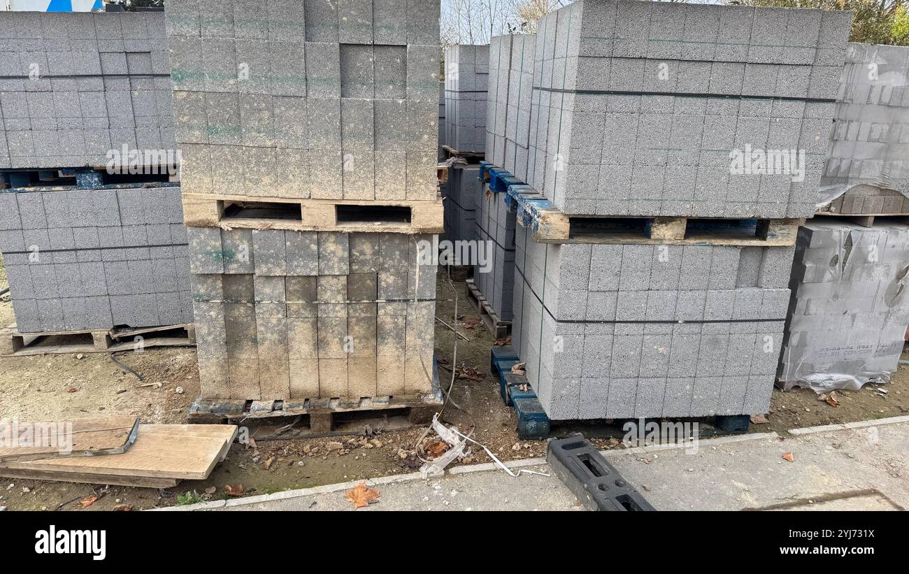 A stack of gray concrete blocks are stacked on wooden pallets. They are ...