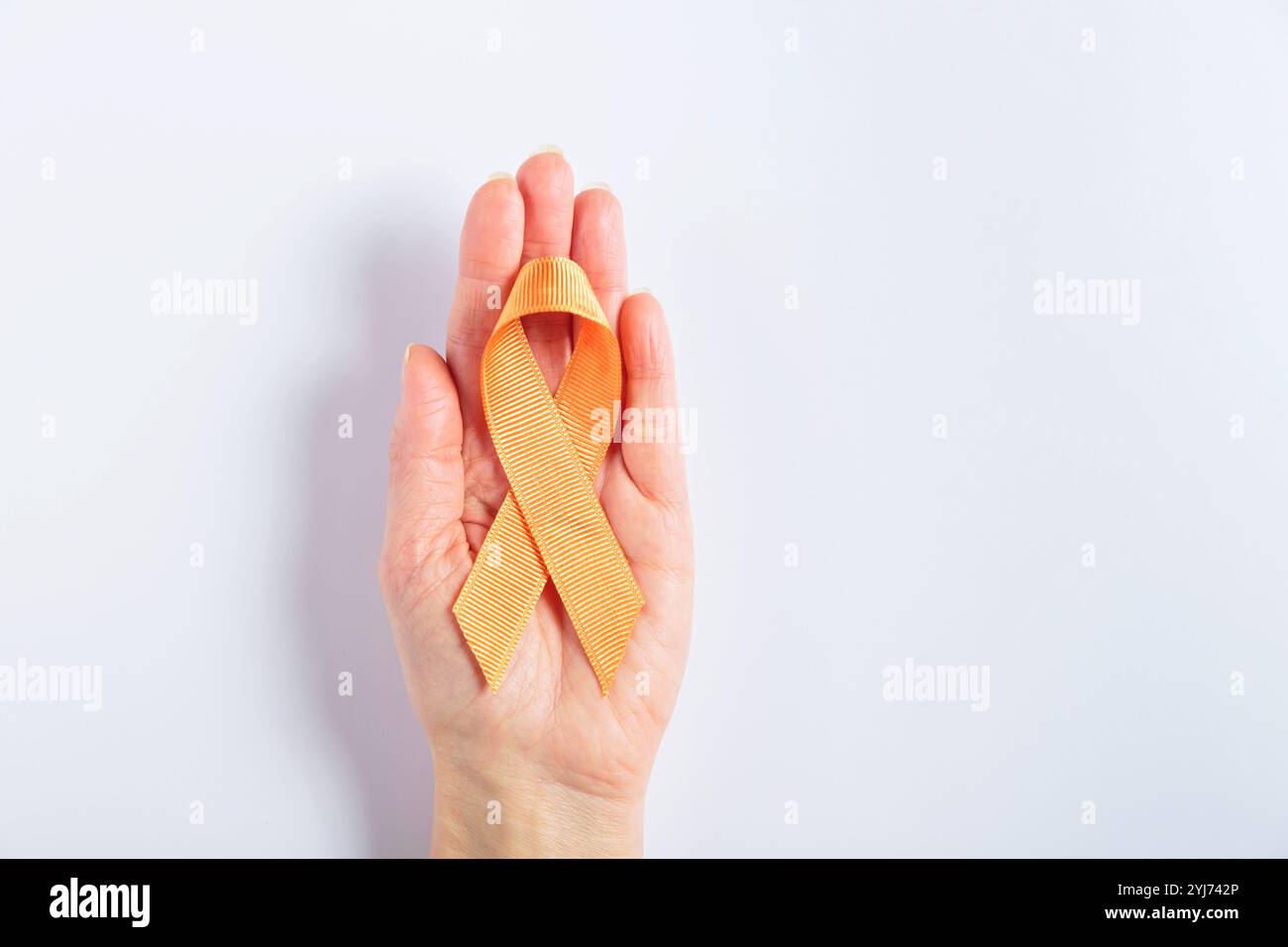 Orange cancer ribbon in womans hand on white background Stock Photo - Alamy