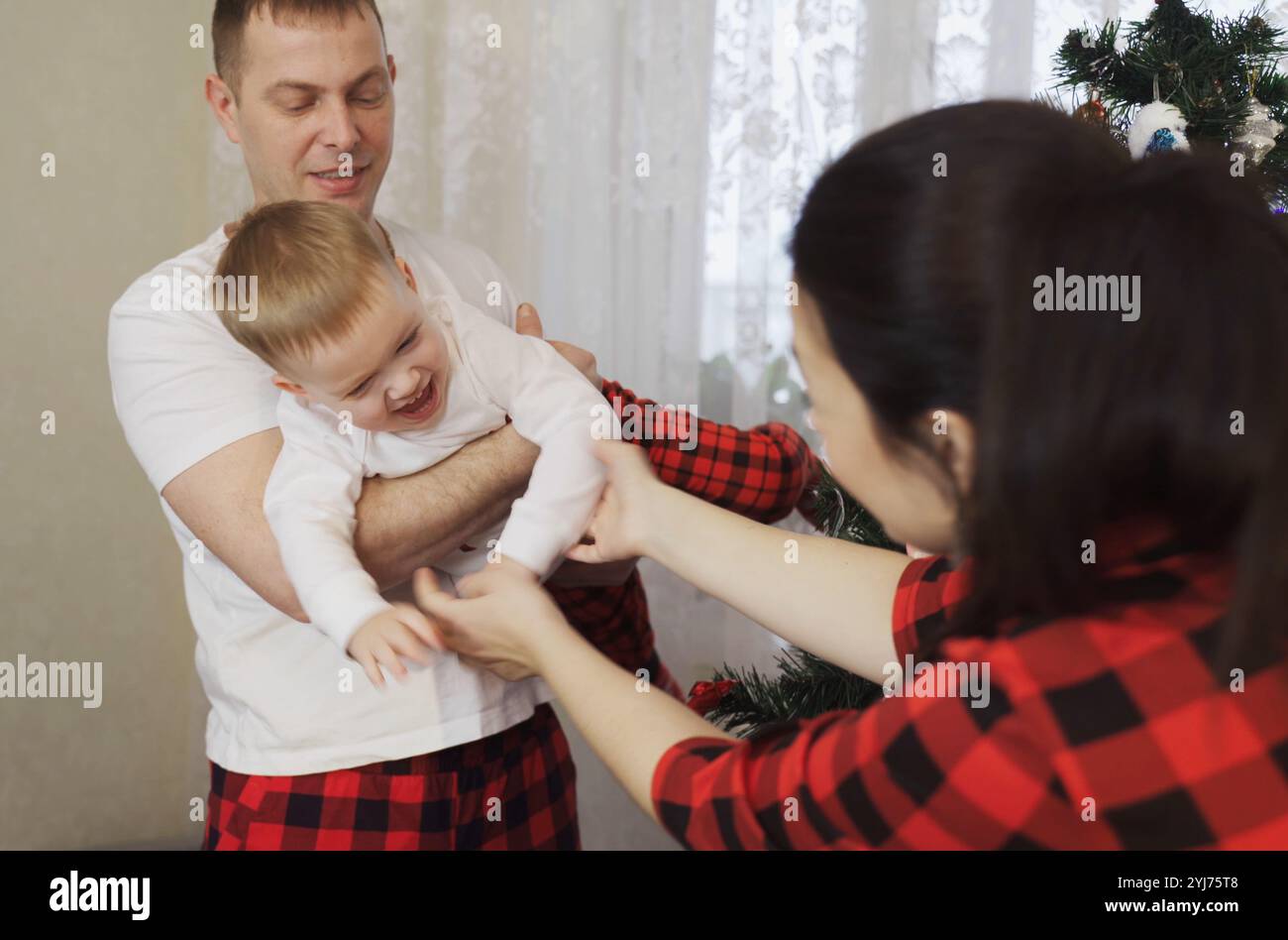 A father lovingly holds his giggling child as a mother playfully ...