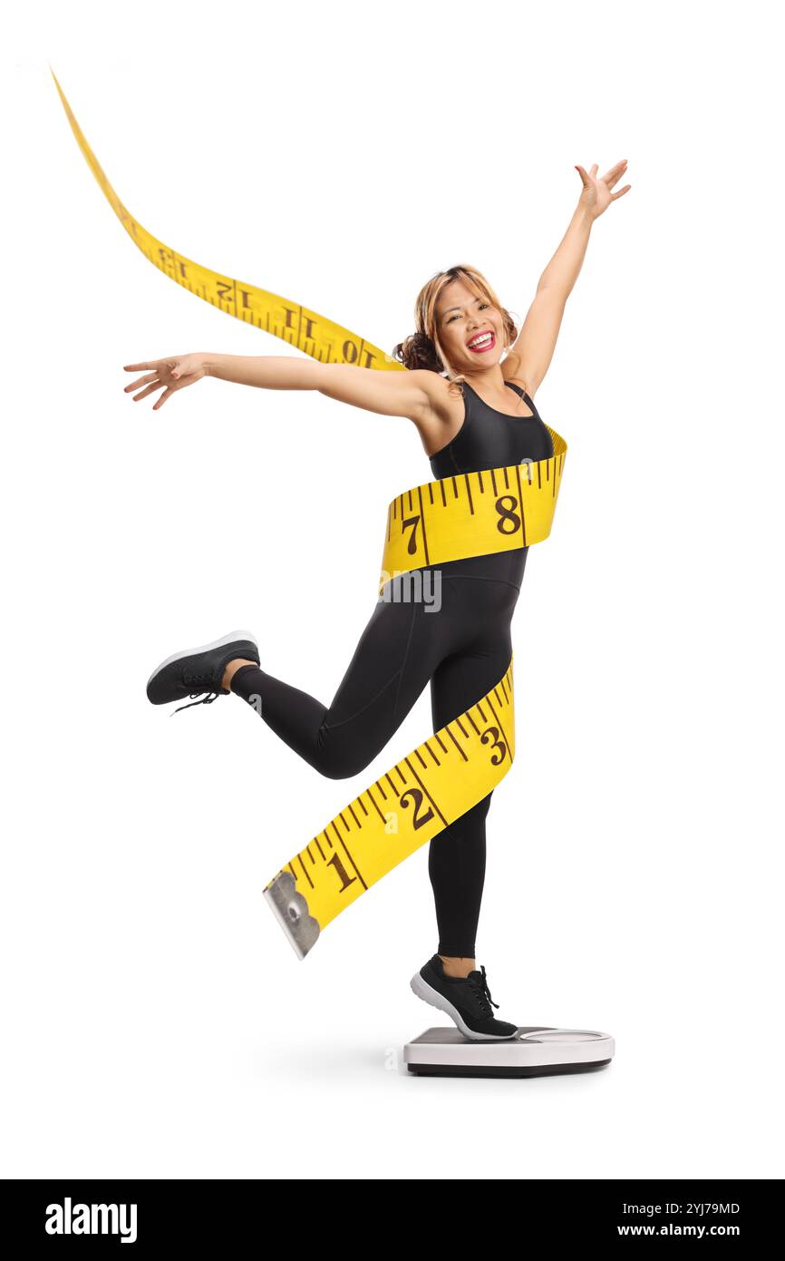 Happy filipina woman in sports clothes standing on a weight scale with ...