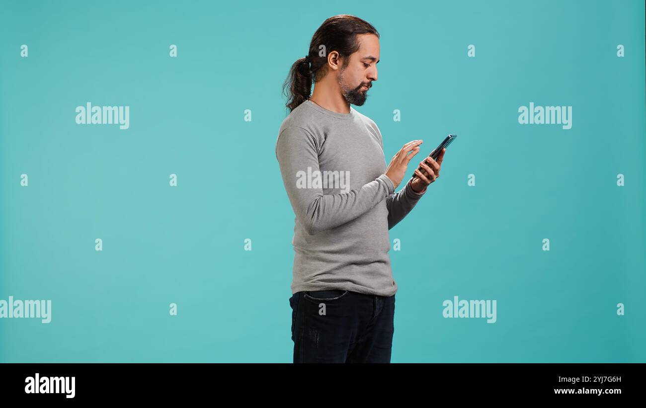 Portrait of smiling man scrolling on smartphone touchscreen, using ...