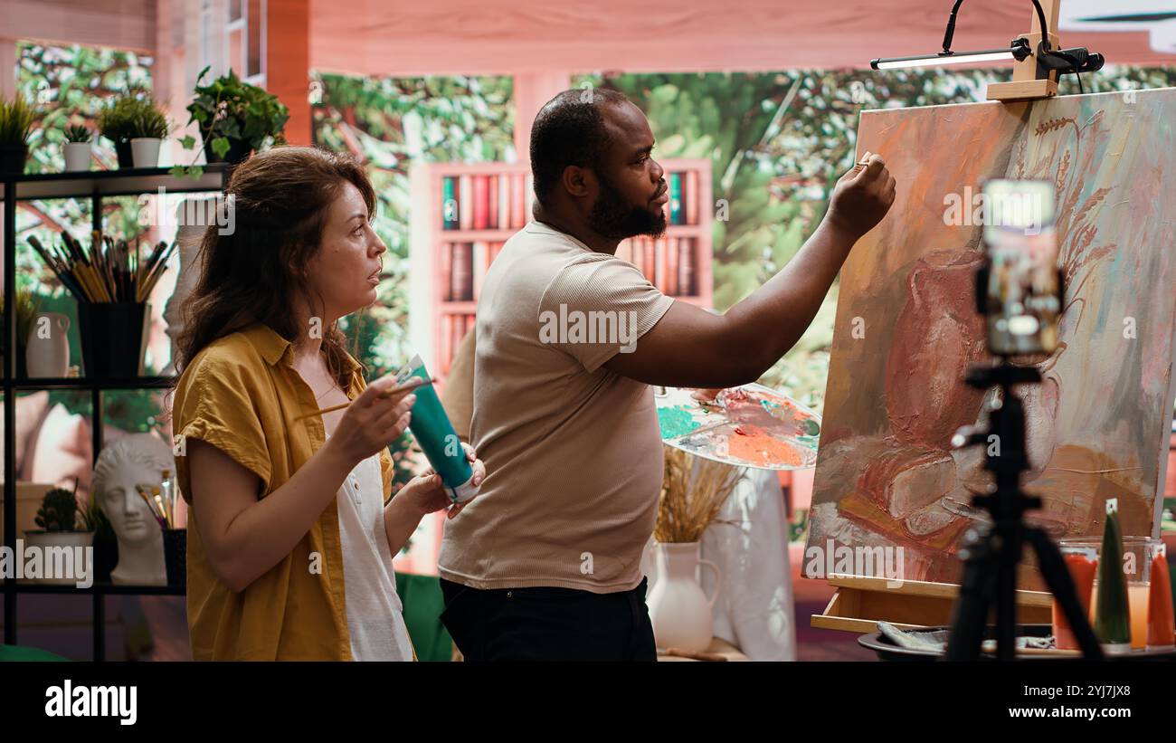 Woman painter filming her colleague during creative process and ...